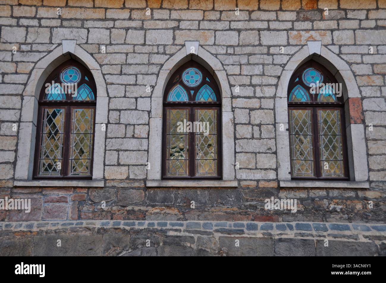 three gothic windows in the natural stone facade Stock Photo - Alamy
