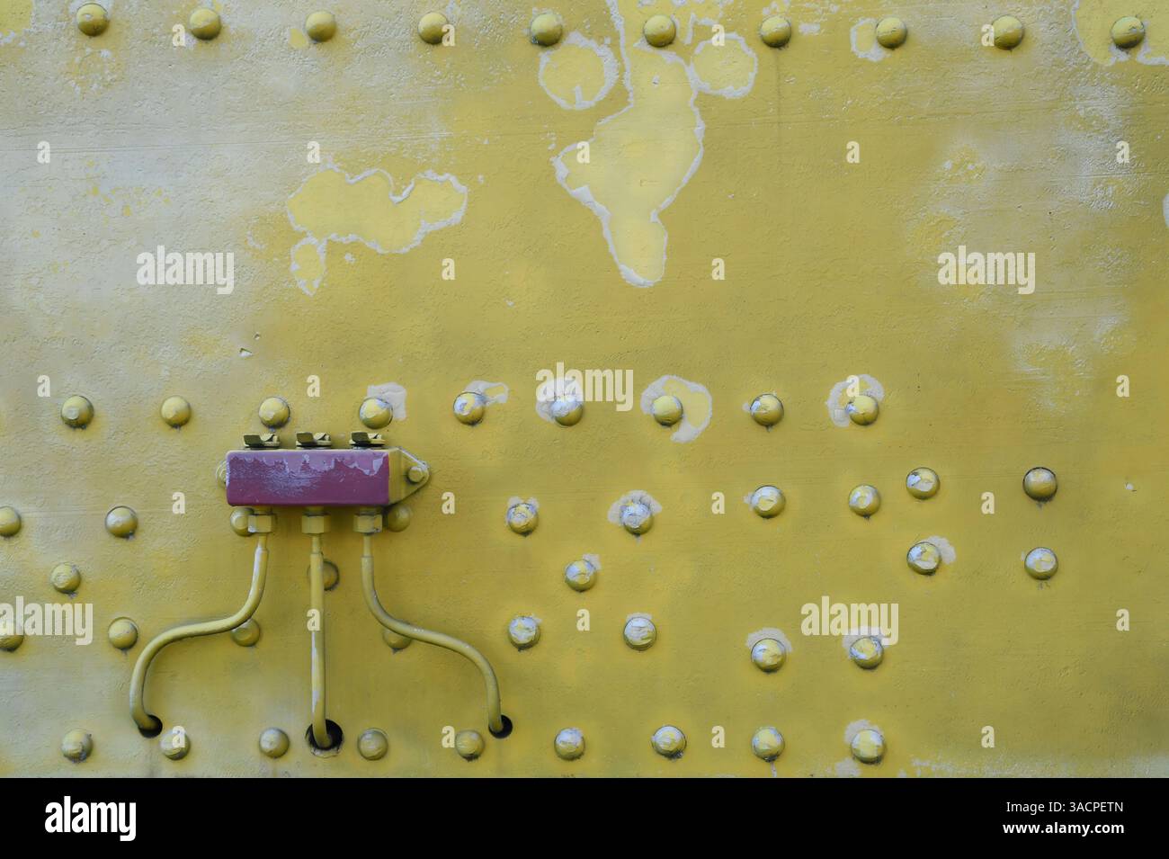 Yellow sheet steel with rivets and hydraulic lines Stock Photo - Alamy
