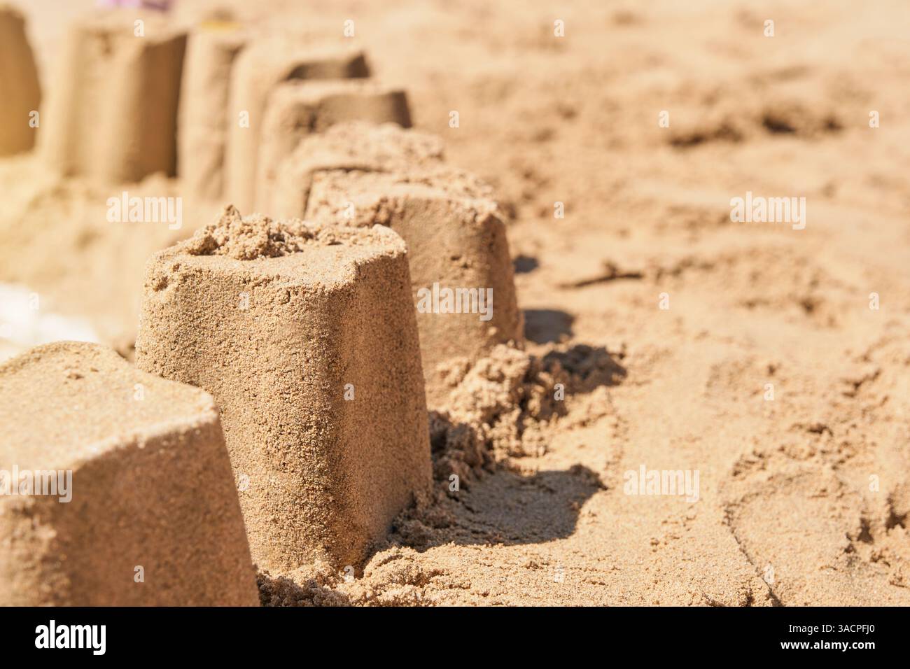 Simple sandcastle on fine sandy beach under the expansive blue sky ...