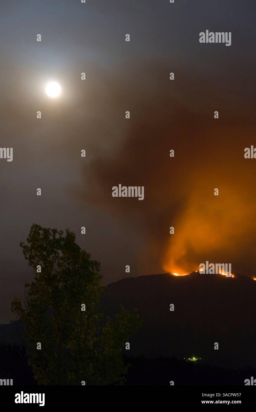 Flames and smoke rising from burning mountain ridge at night with full ...