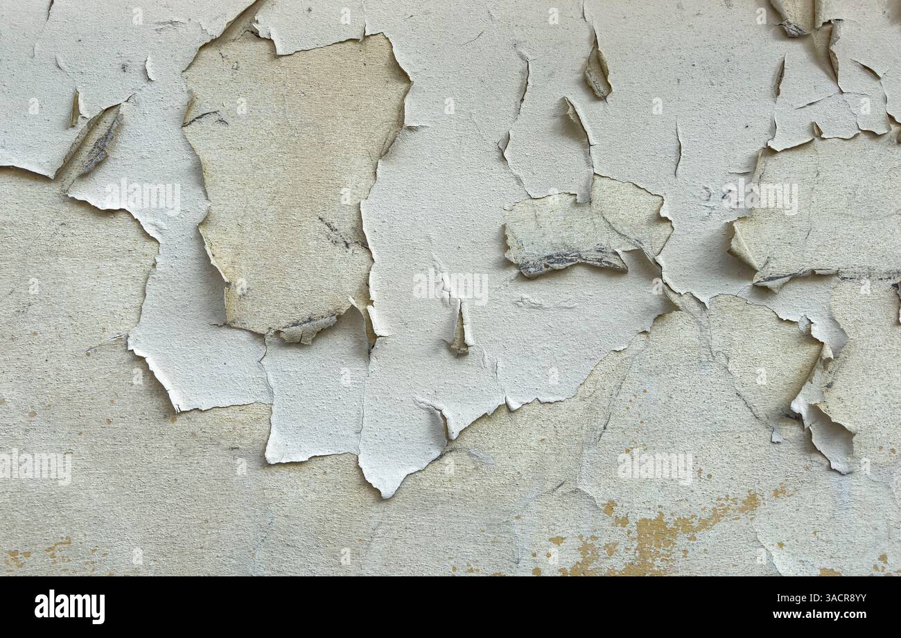 Peeling paint on an aged wall reveals layered textures and patterns, adding rustic charm to the ...
