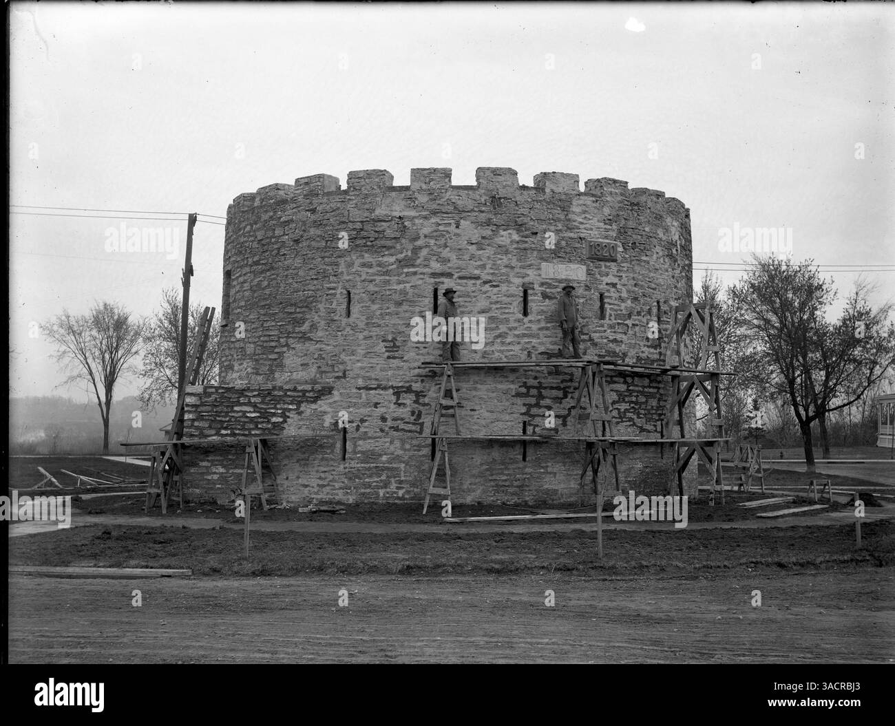 Two workers remove concrete from the sides of the Round Tower at Fort ...