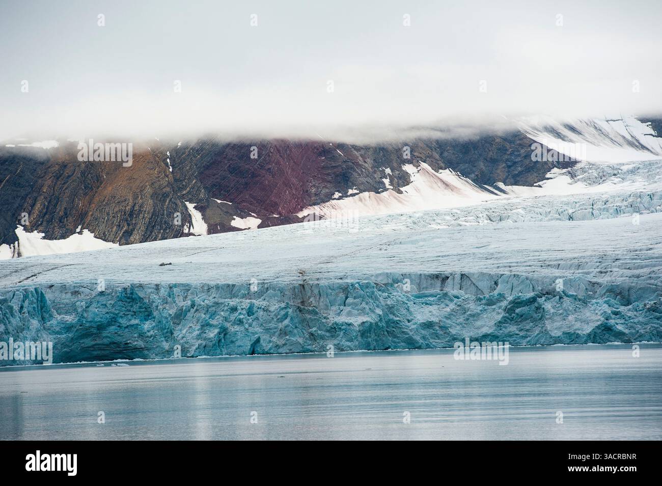 Spectacular coastal landscape with blue glacier ice and colorful rock ...