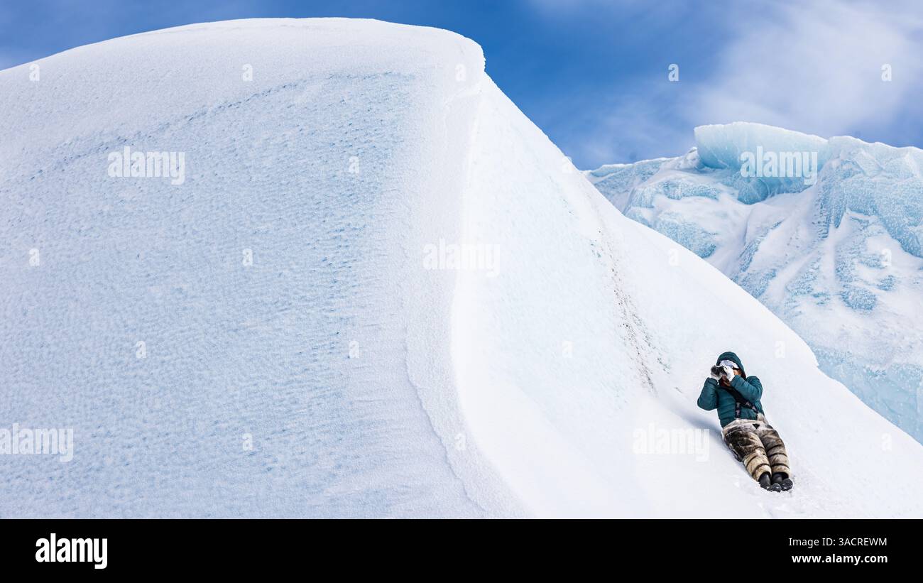 Anonymous Inuit guide with binoculars searching for polar bears rom the ...