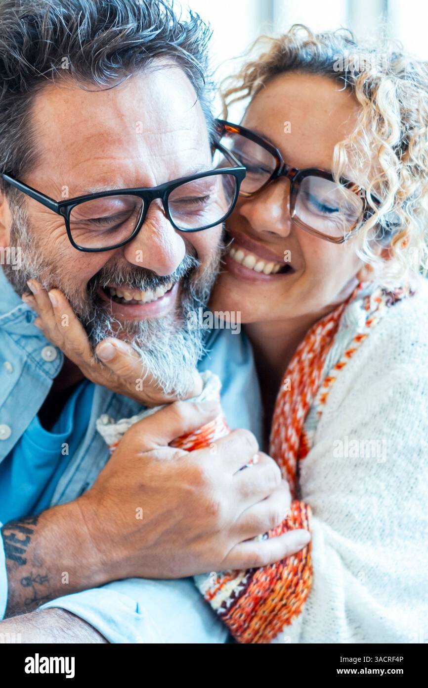 An adult couple in their late 40s, wearing glasses, smiling and ...