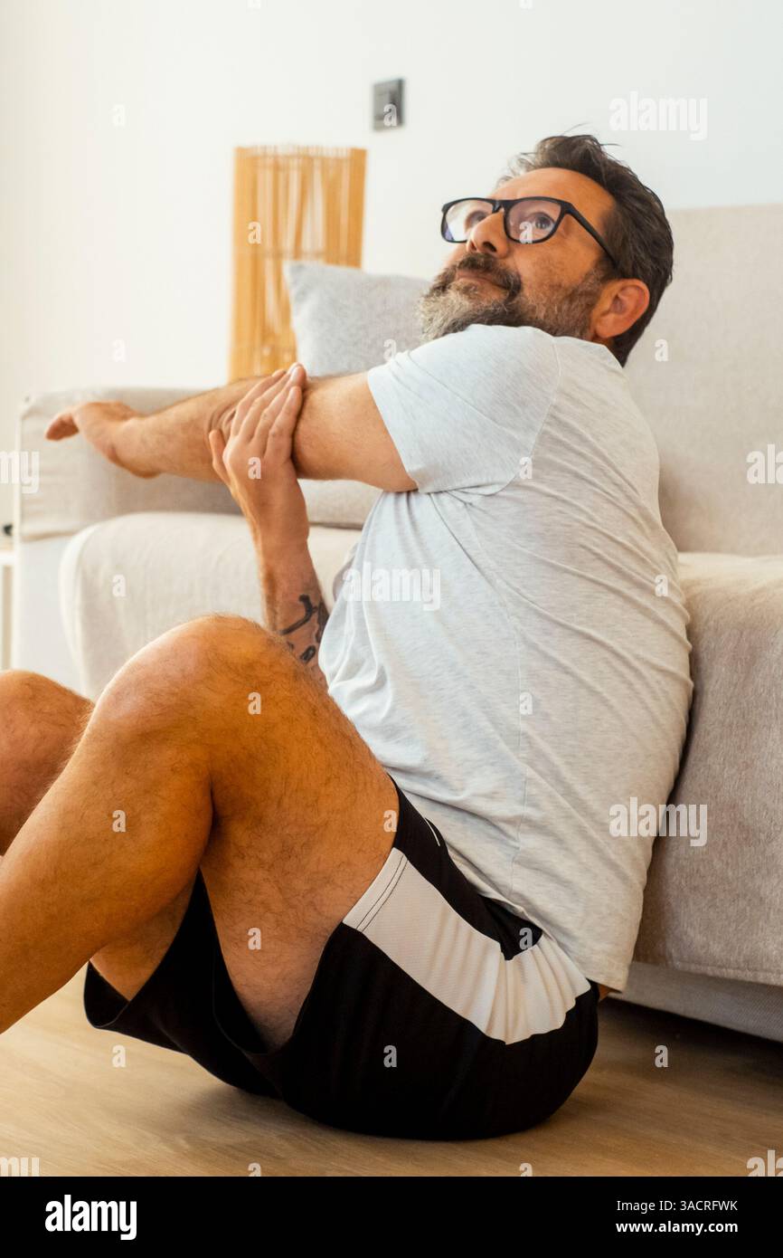 An adult man performing a full-body workout at home with gym equipment ...