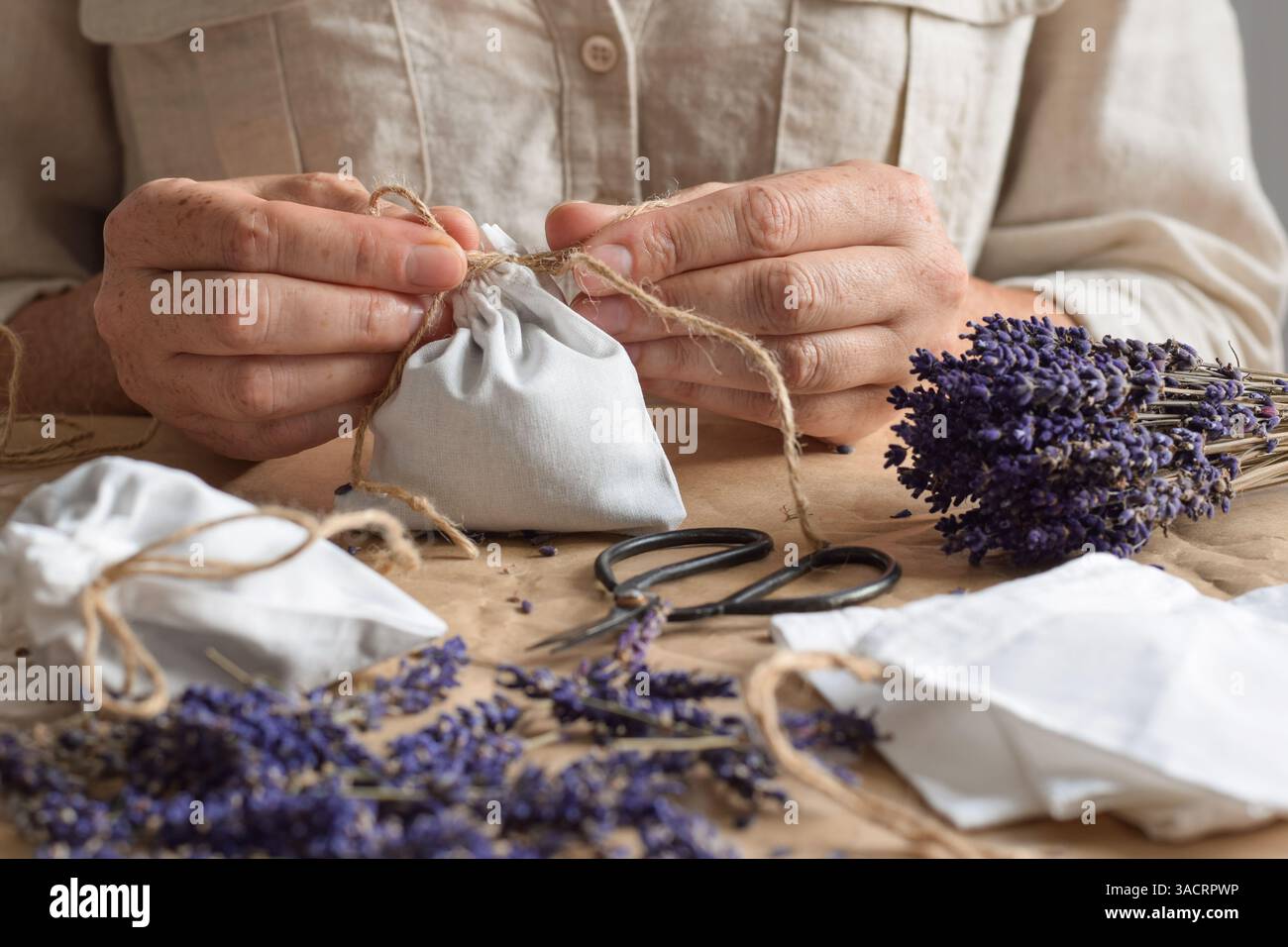 Woman tying a string on diy lavender sachet Stock Photo - Alamy