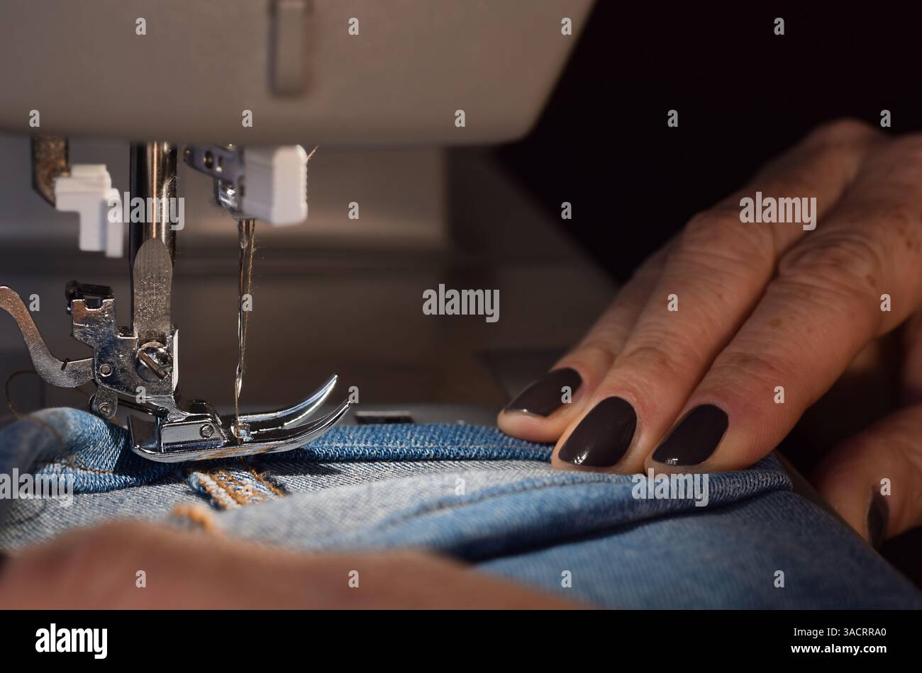 Seamstress using sewing machine for hemming jeans closeup Stock Photo ...