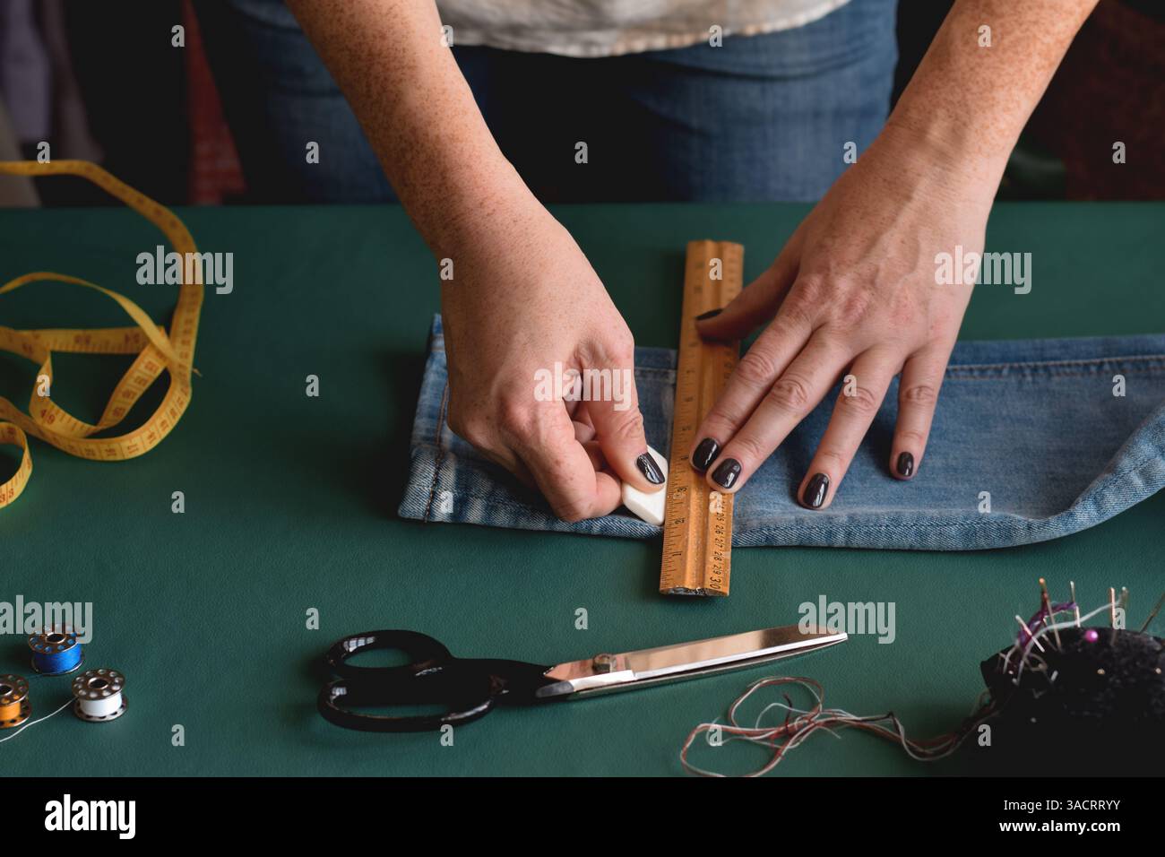 Seamstress marking jeans length for hemming Stock Photo - Alamy