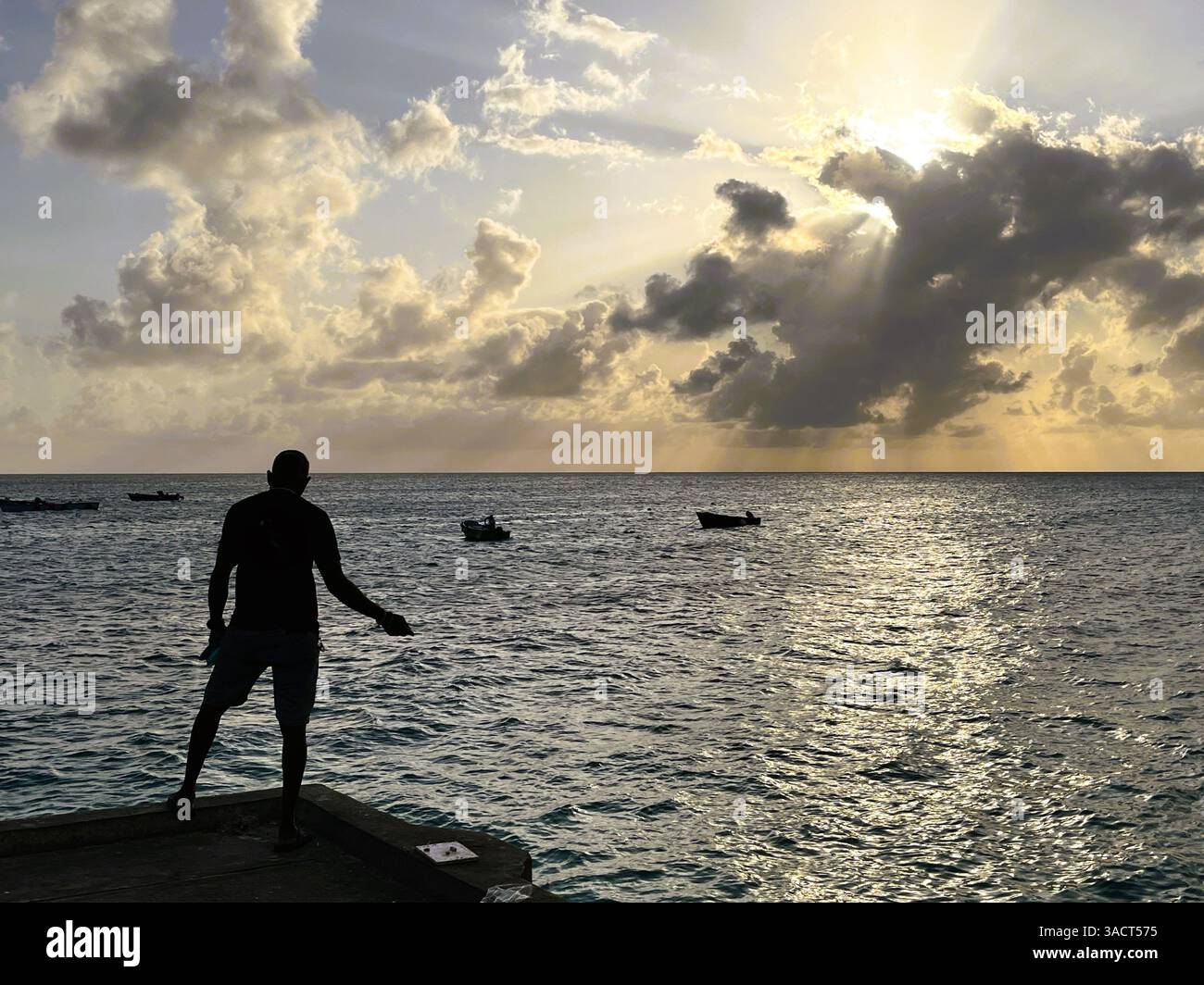 Oistins, Barbados - January 04, 2025: As the sun sets, a fisherman ...