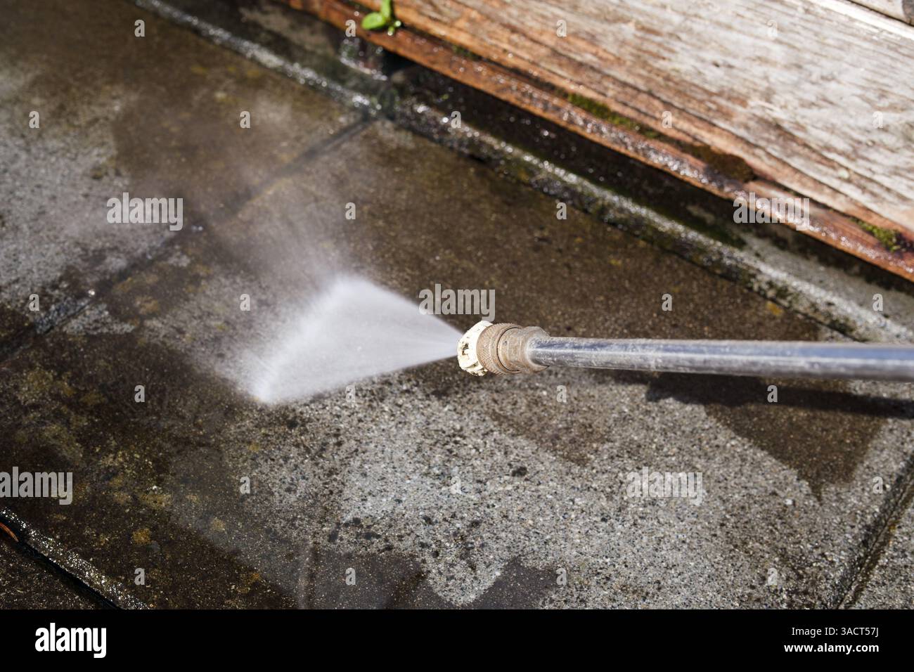 Concrete tile cleaning with pressure washer. Close up of high pressure ...