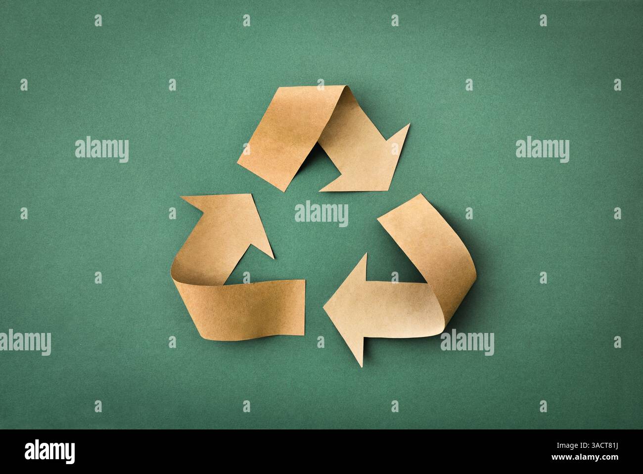 Recycling symbol with arrows made of brown paper on a green textured ...