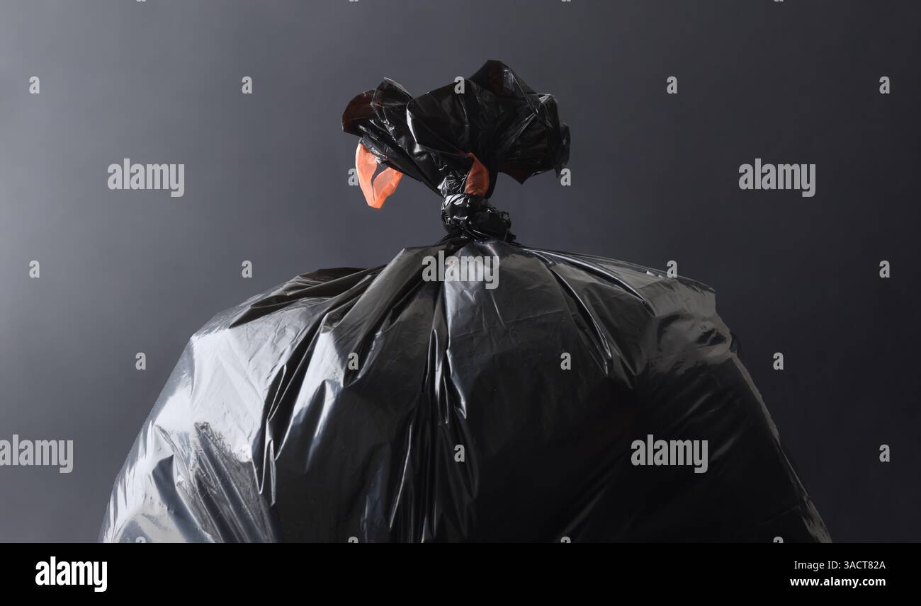 Detail of a full black plastic garbage bag closed with a knot and a ...