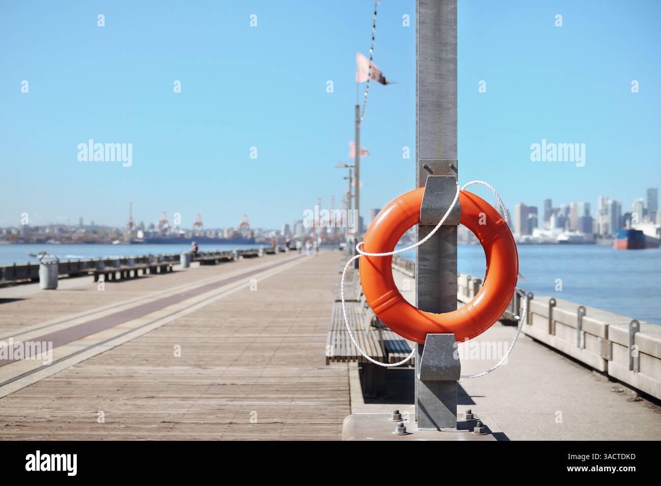 Orange life buoy or preserver on pier with defocused ocean and ...