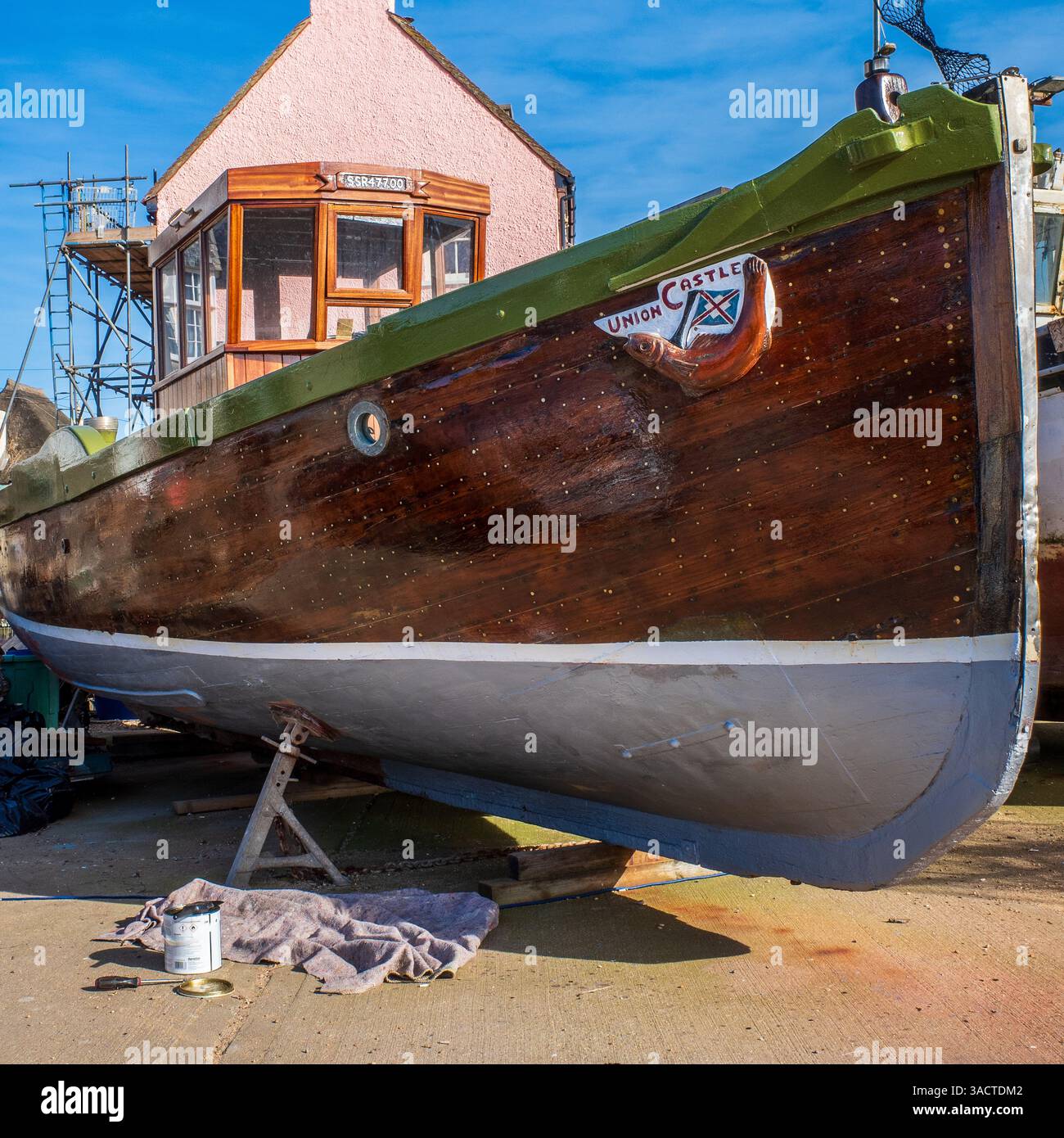 Dry docked fishing boat on West Bay quayside getting its hull painted ...