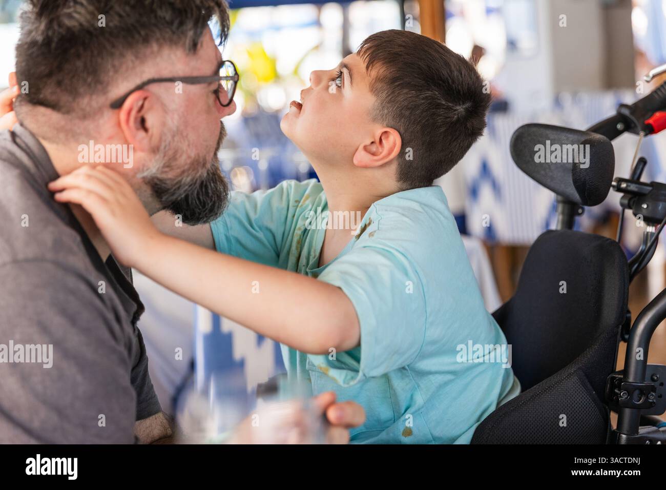 Disabled child embracing father in restaurant, cerebral palsy awareness ...