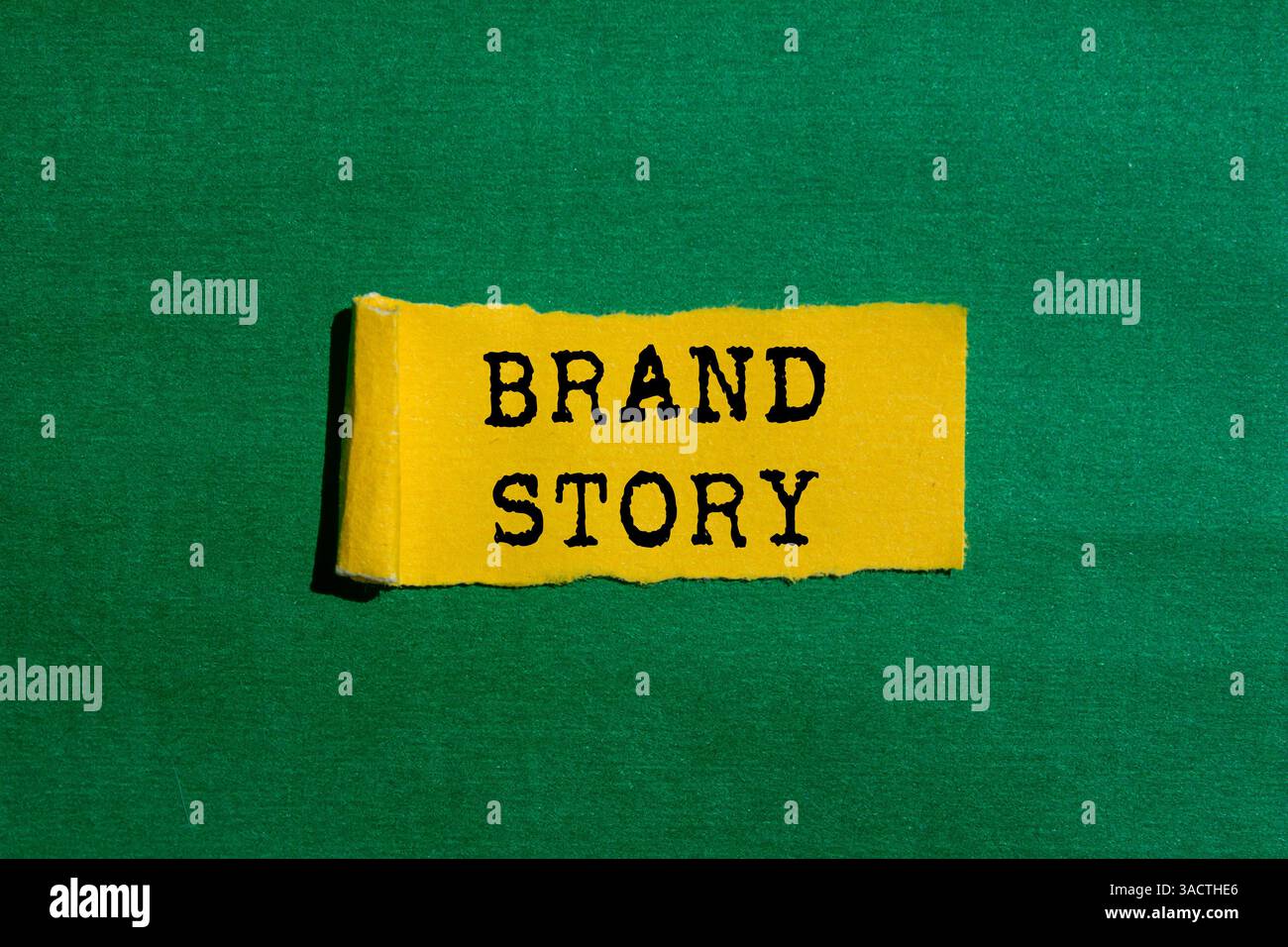 Brand story message written on ripped torn yellowpaper piece on green ...