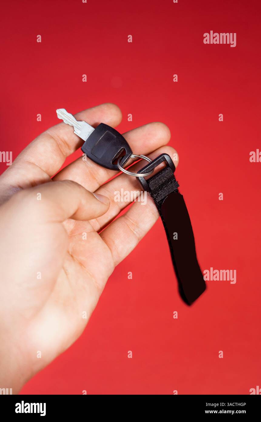 A boy holding a black fabric keychain with a key in his hand, isolated ...