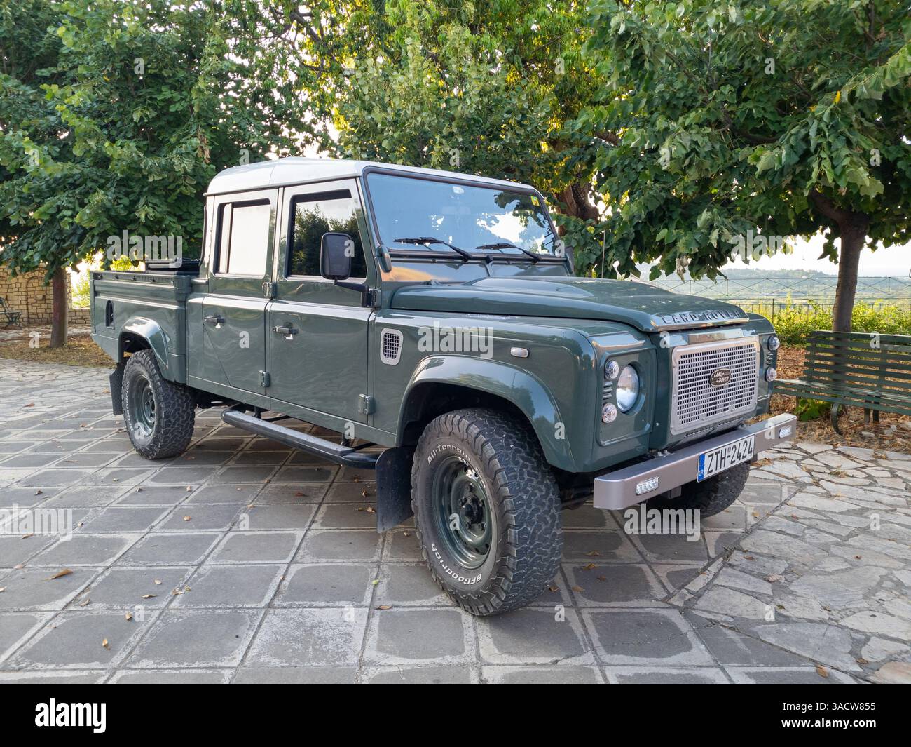 Green utility vehicle with a white roof, parked on a paved surface ...