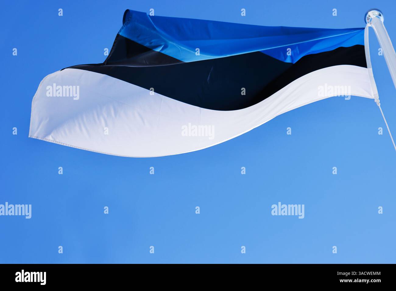 Flag of Estonia flying against bright blue sky with white clouds ...
