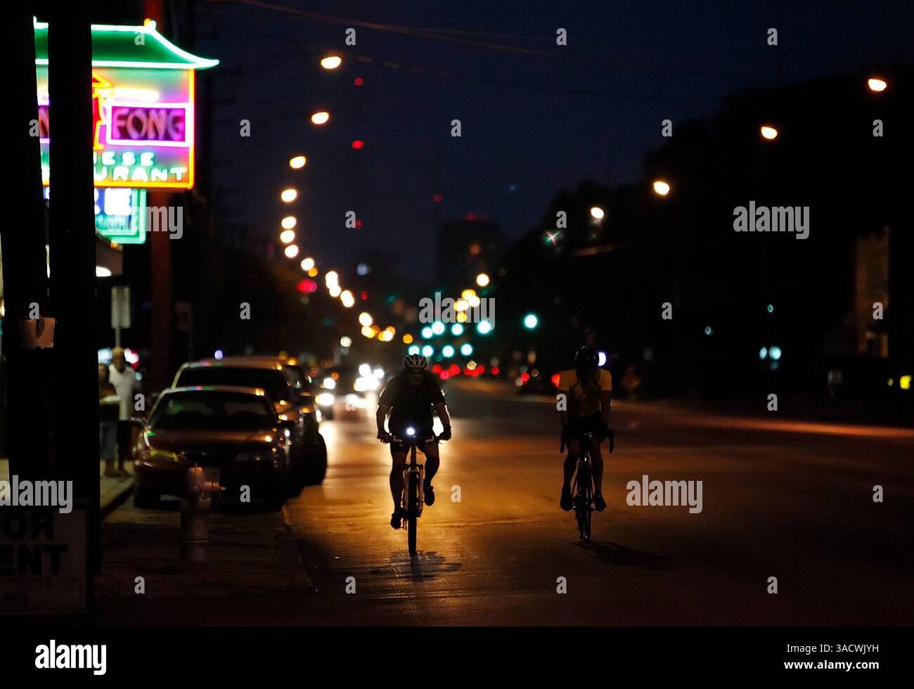Cyclists proceed in the dark along Broadway Avenue nearing their ...