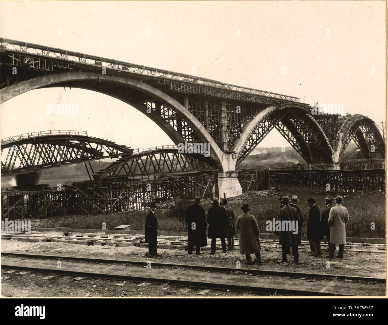 The Mendota Bridge under construction is observed by a group of men ...