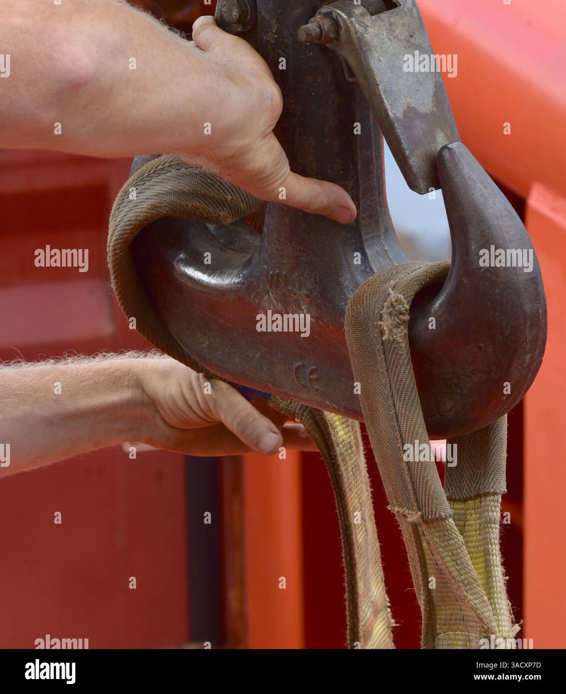 Tight shot of crane's hook and unloading cargo straps attached to hook ...