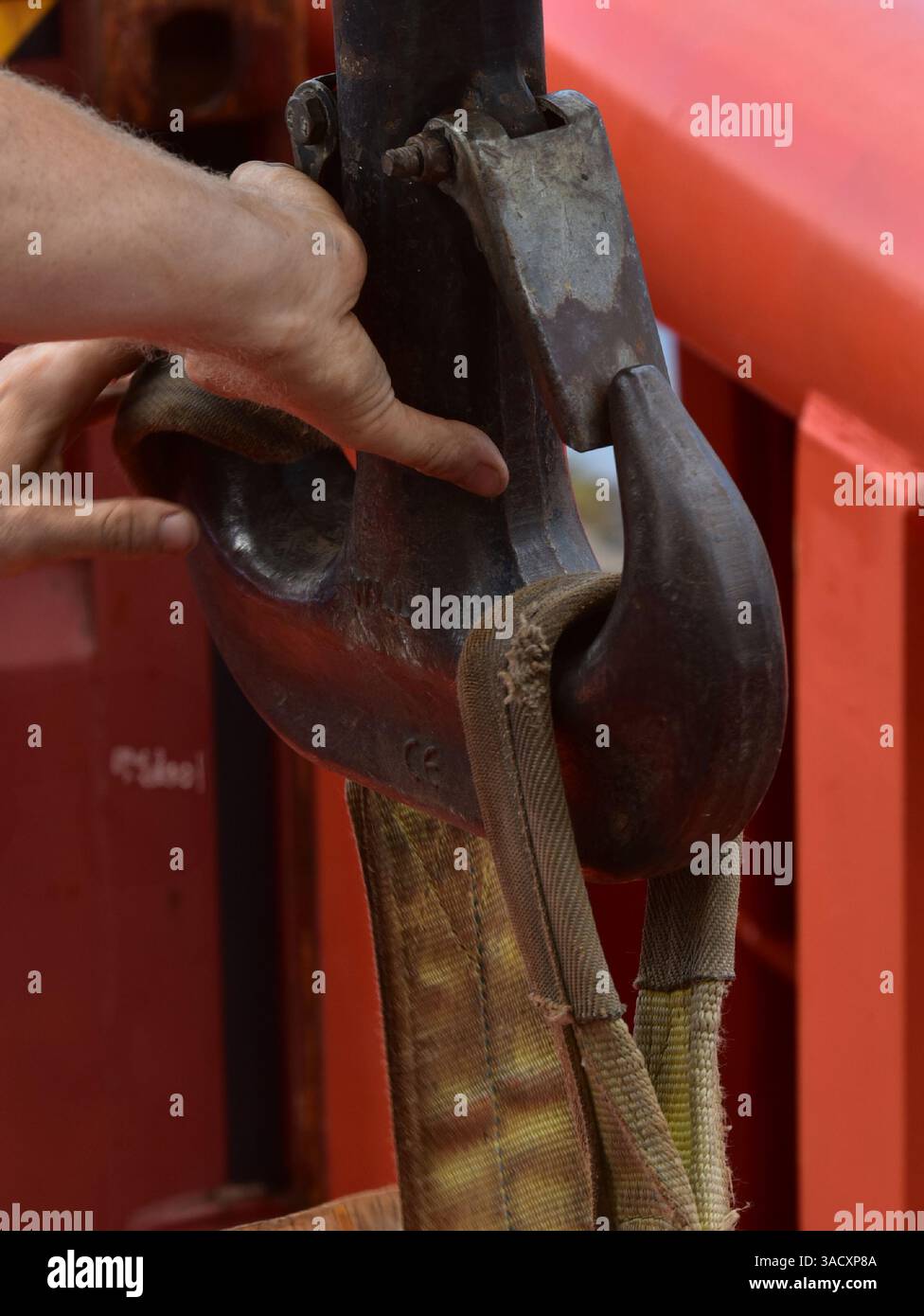 Tight shot of crane's hook and unloading cargo straps attached to hook ...
