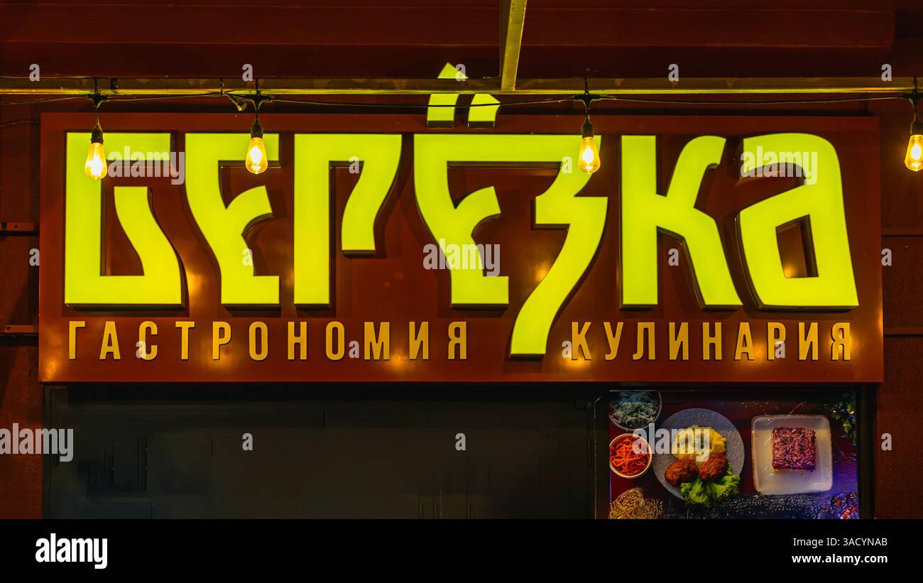 Night city shopfront with bright neon sign reading Berezka above ...