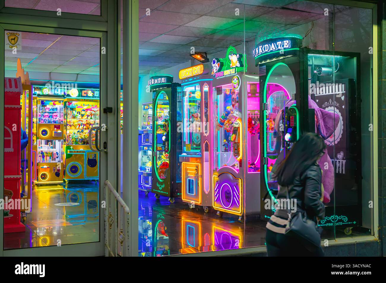 Colorful arcade machines glowing inside bright game room with claw toys ...