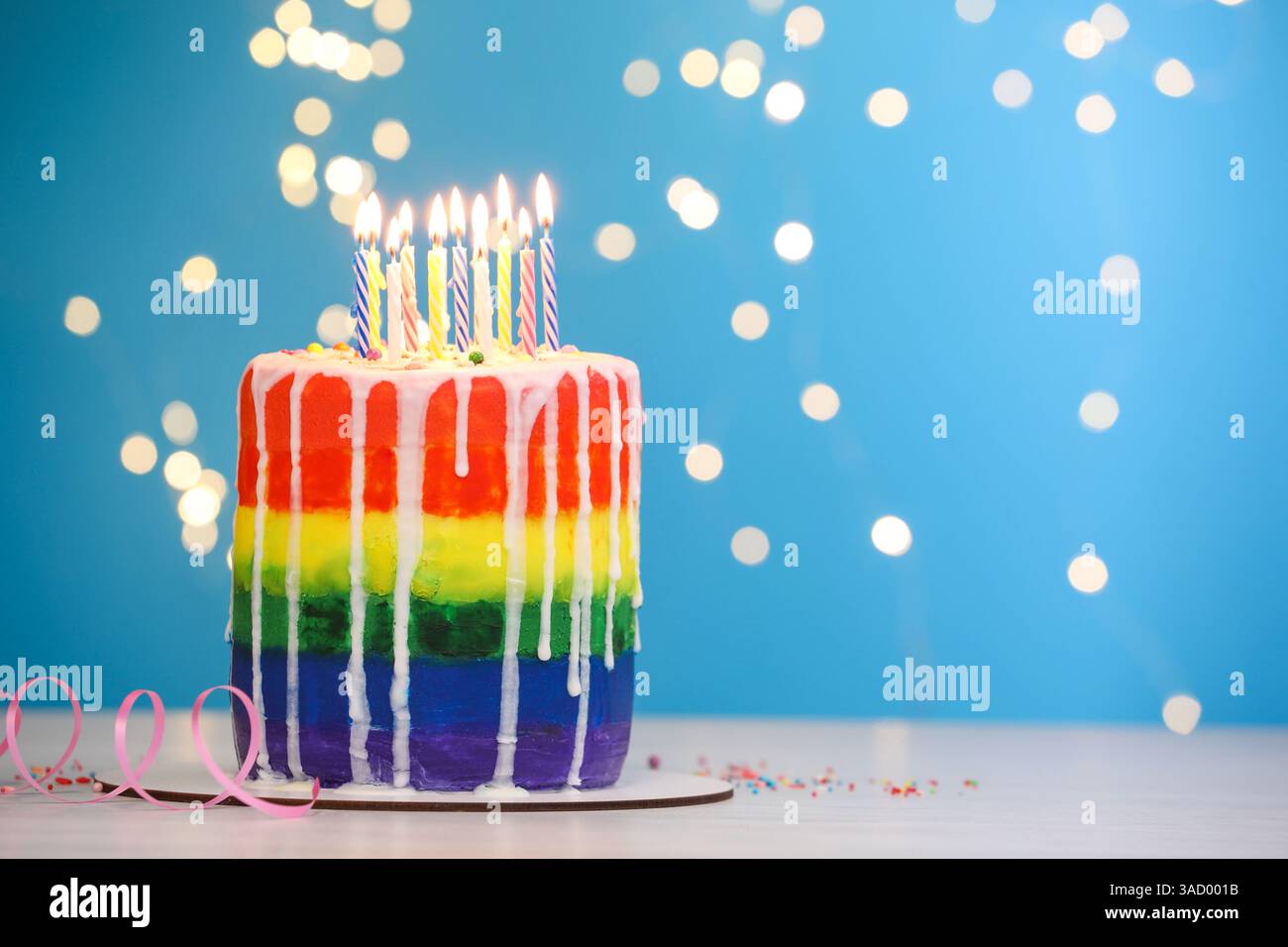Delicious rainbow birthday cake with burning candles, sprinkles and ...
