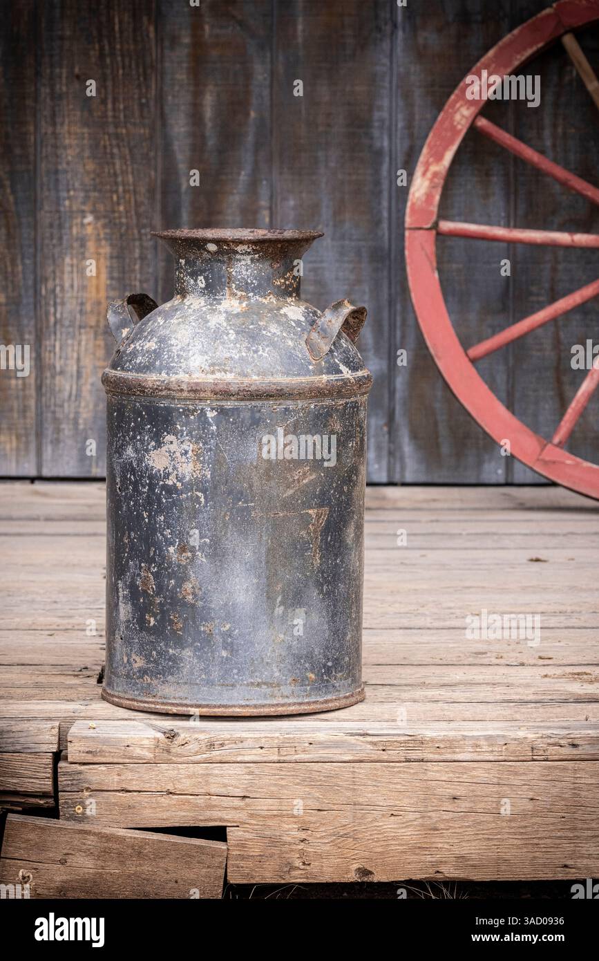 Still-life of old milk can and wagon wheel Stock Photo - Alamy