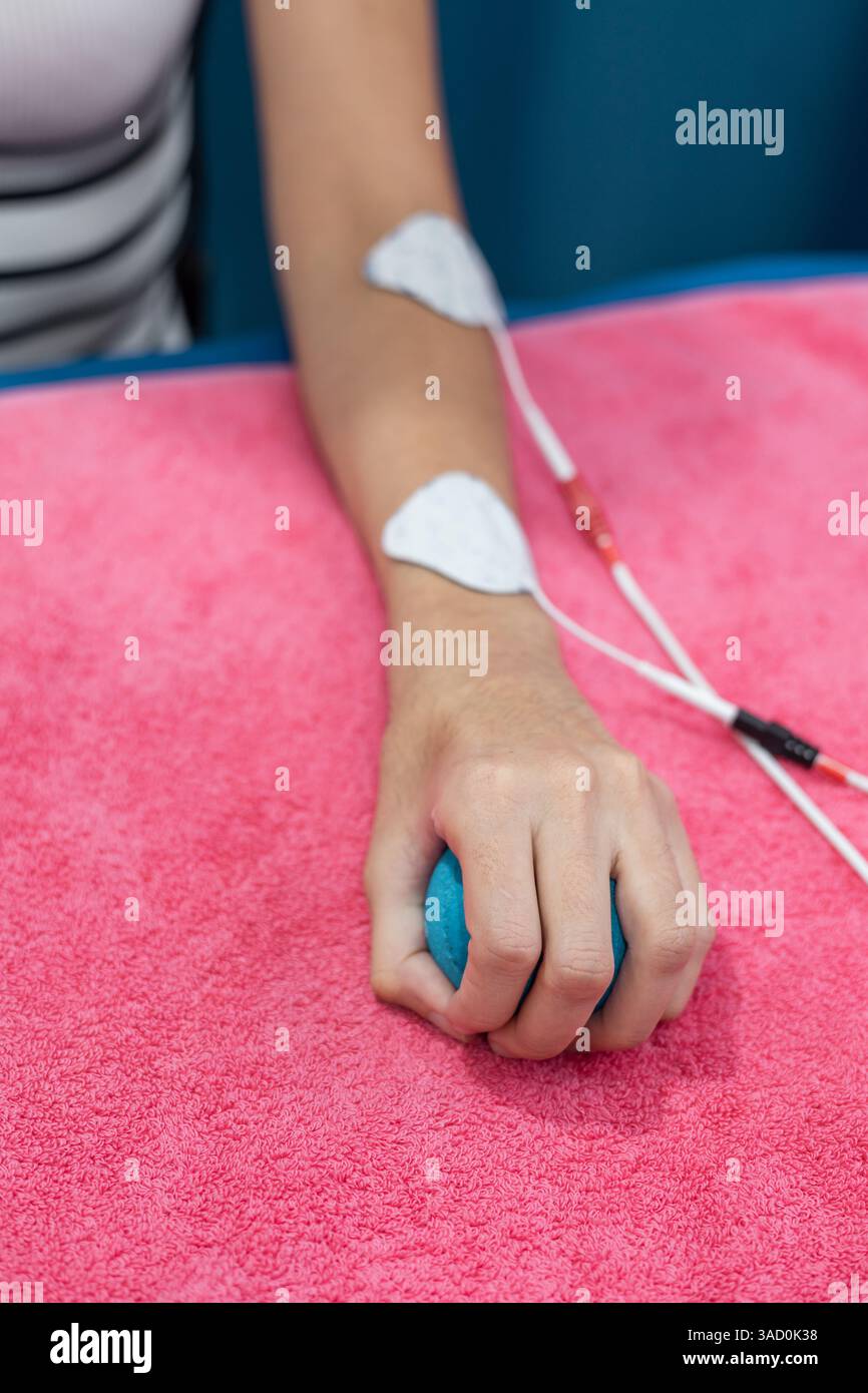 Electrotherapy pulses awaken her hand. Every session brings her closer ...