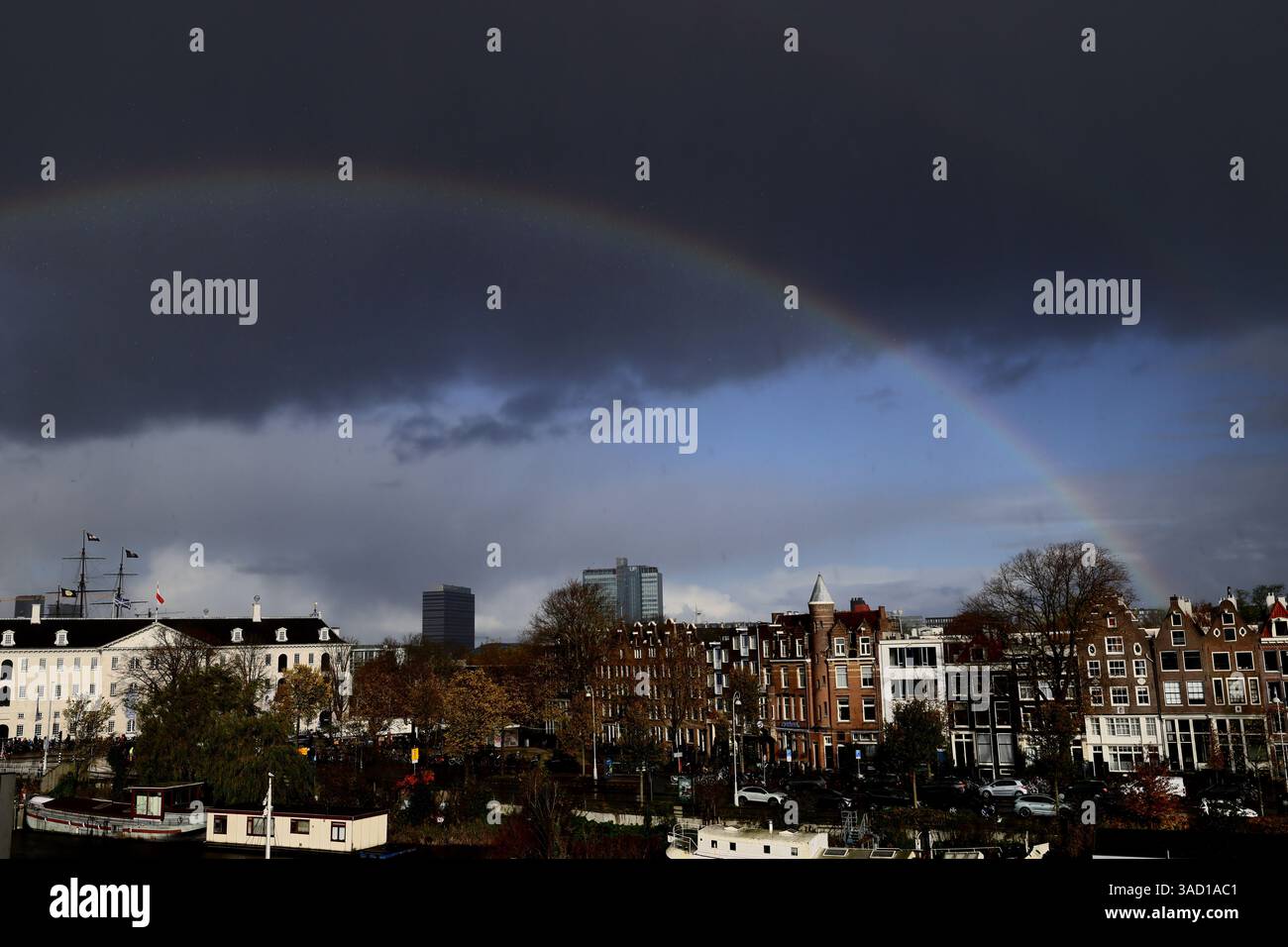 A vibrant rainbow stretches across the dramatic Amsterdam sky, with the historic ...