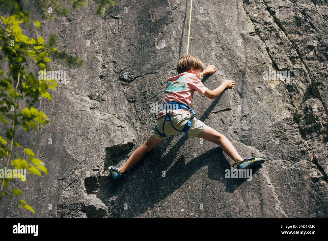 Boy climbing a rock face Stock Photo - Alamy