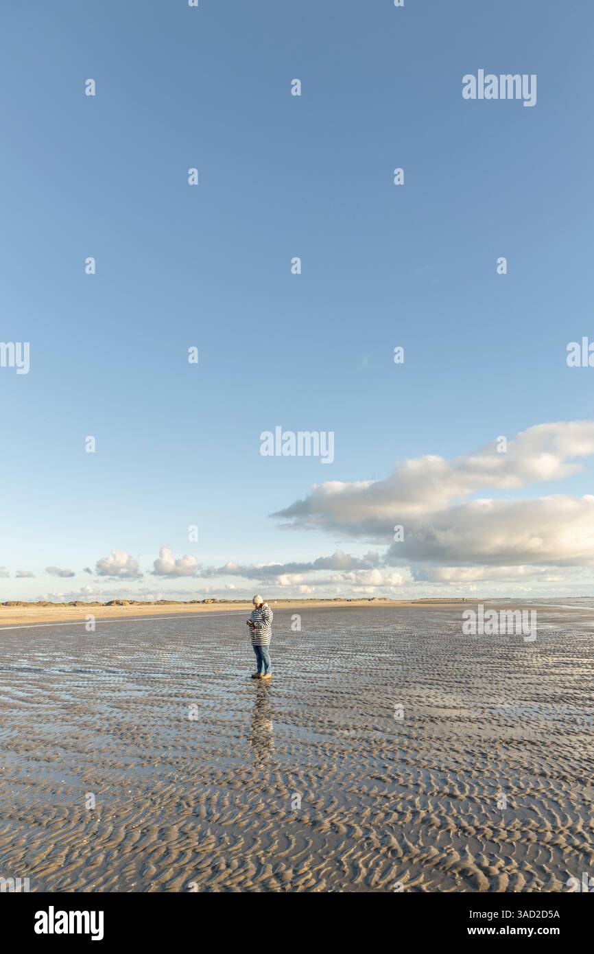 A female person in warm clothes stands alone in the middle of the ...