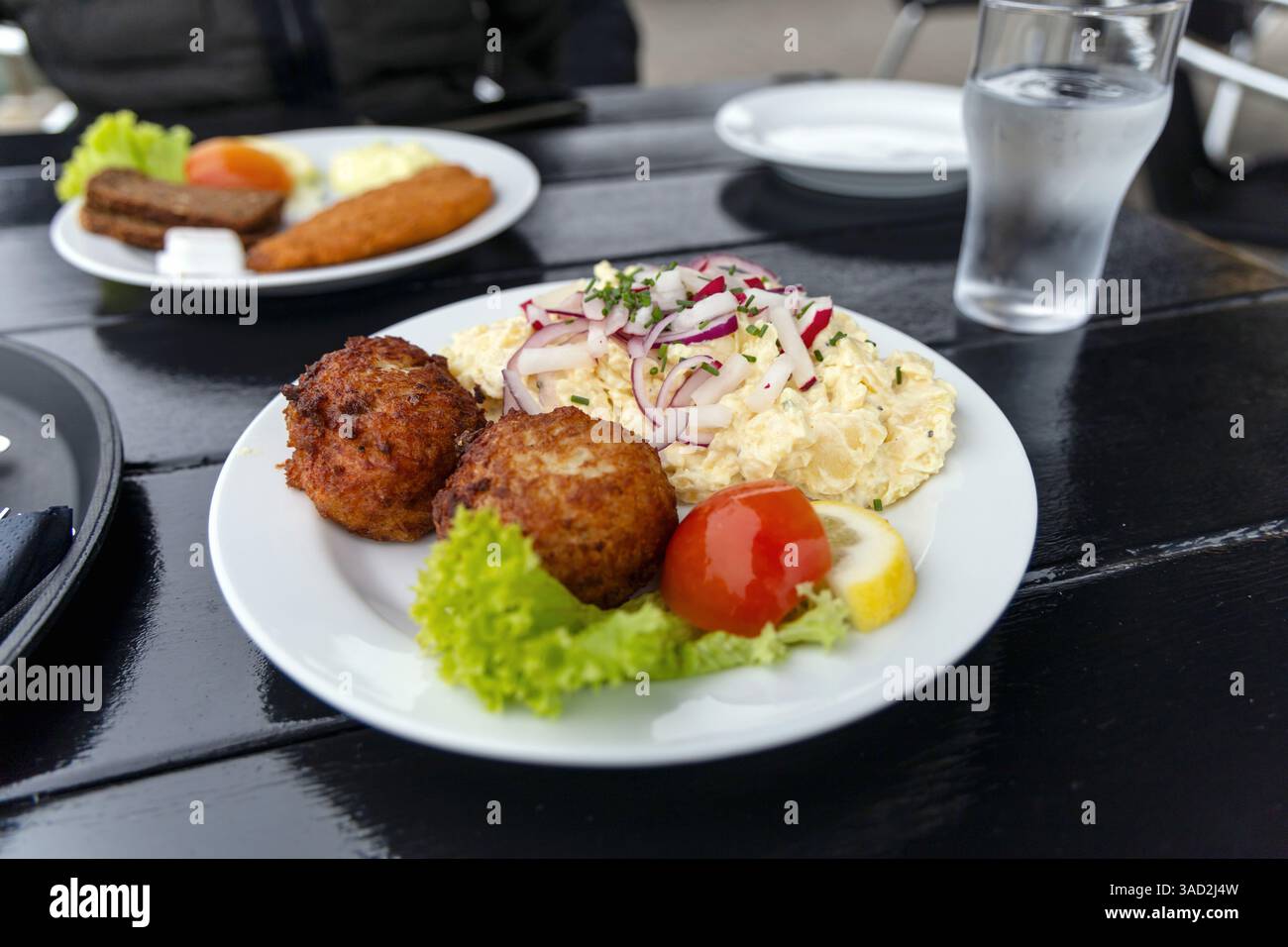 Seafood restaurant on the seashore. White plate with fish patties, fish ...
