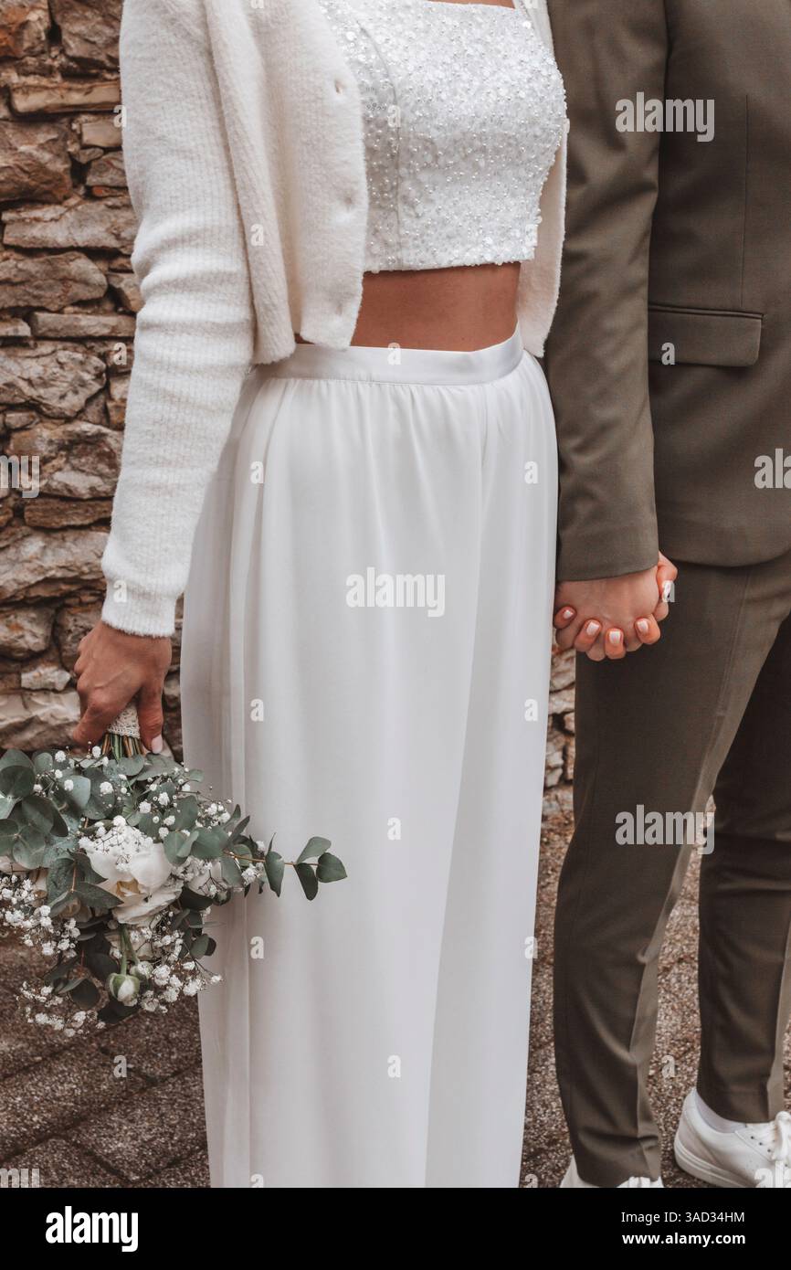 Bride and groom standing next to each other, bride wearing a belly ...