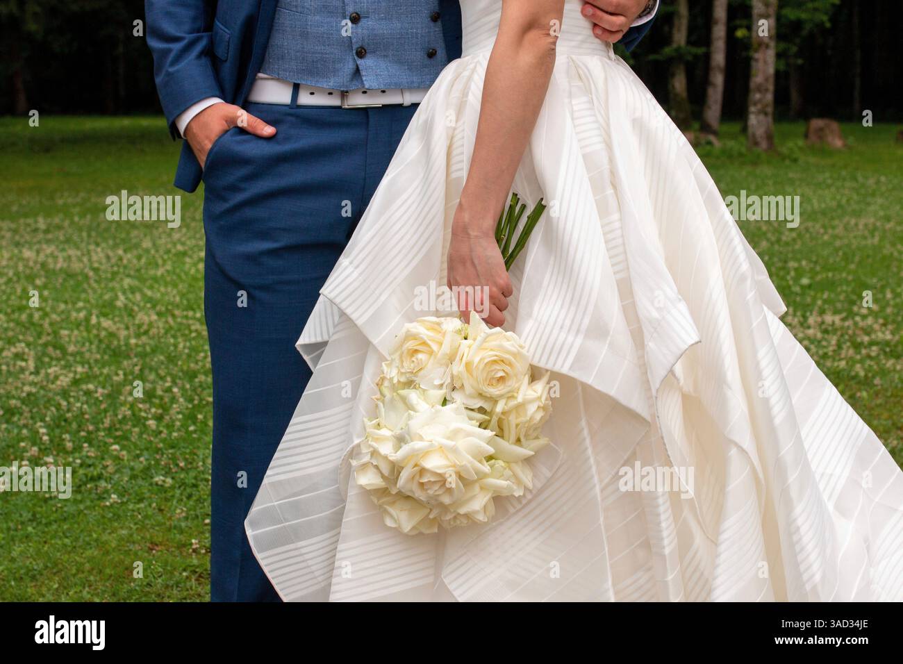 Couple at photo shoot, bride leaning against groom in blue suit ...