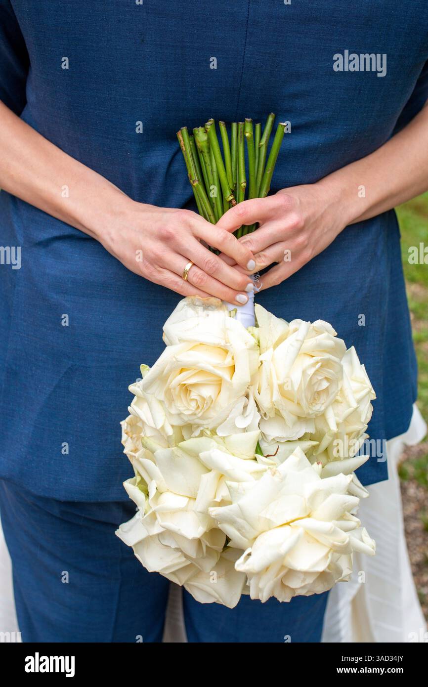Couple at photo shoot, bride hugging groom in blue suit, holding bridal ...