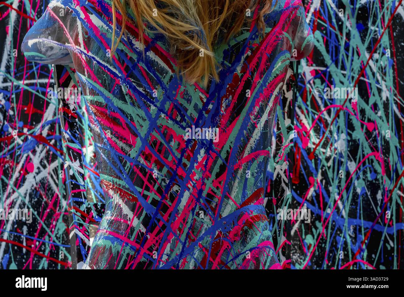 A model poses gracefully, her body adorned in vibrant body paint, with brilliant, sweeping ...