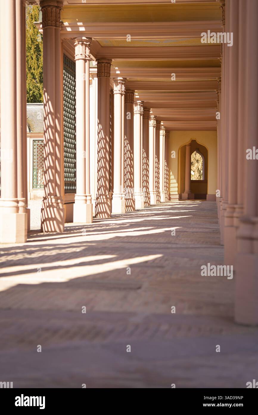 Long colonnade with openwork play of light from the sun in warm pink ...