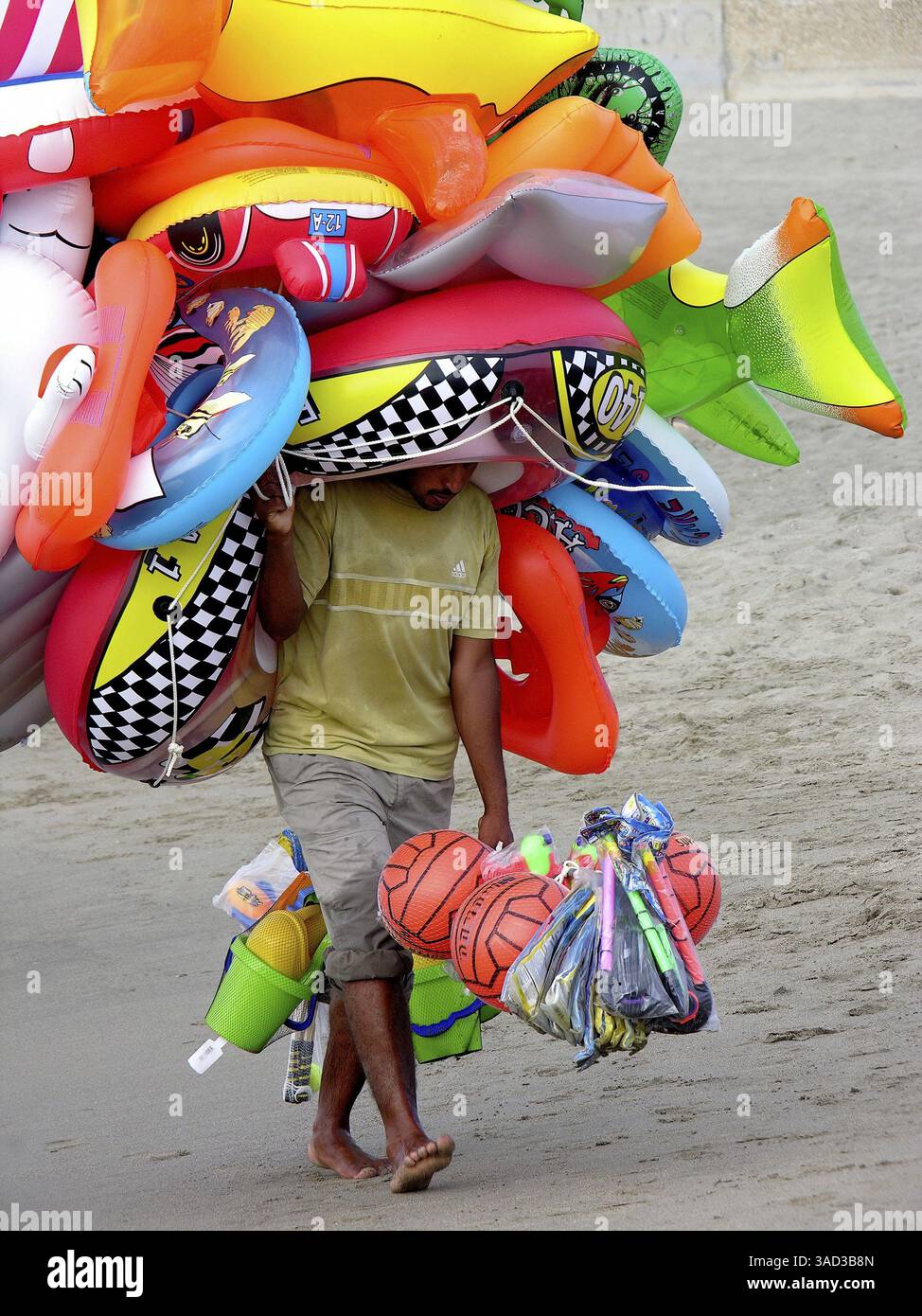 Flying merchant, seller overloaded with large quantities of beach toys ...
