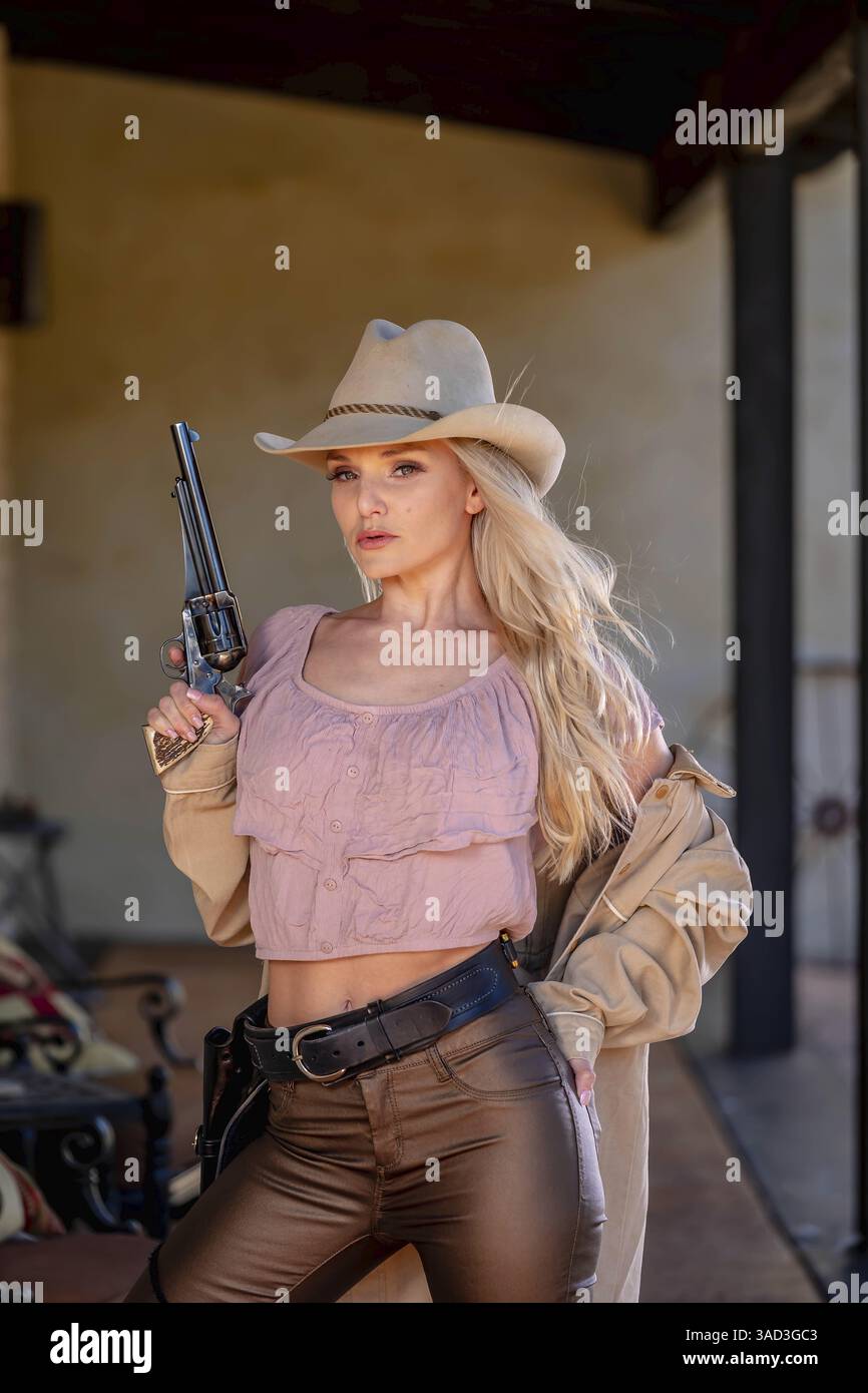 A confident, beautiful blonde woman in classic cowboy attire stands ...