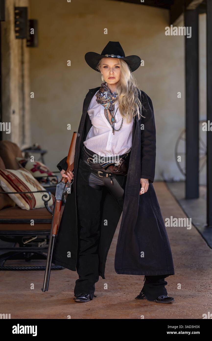 A confident, beautiful blonde woman in classic cowboy attire stands ...