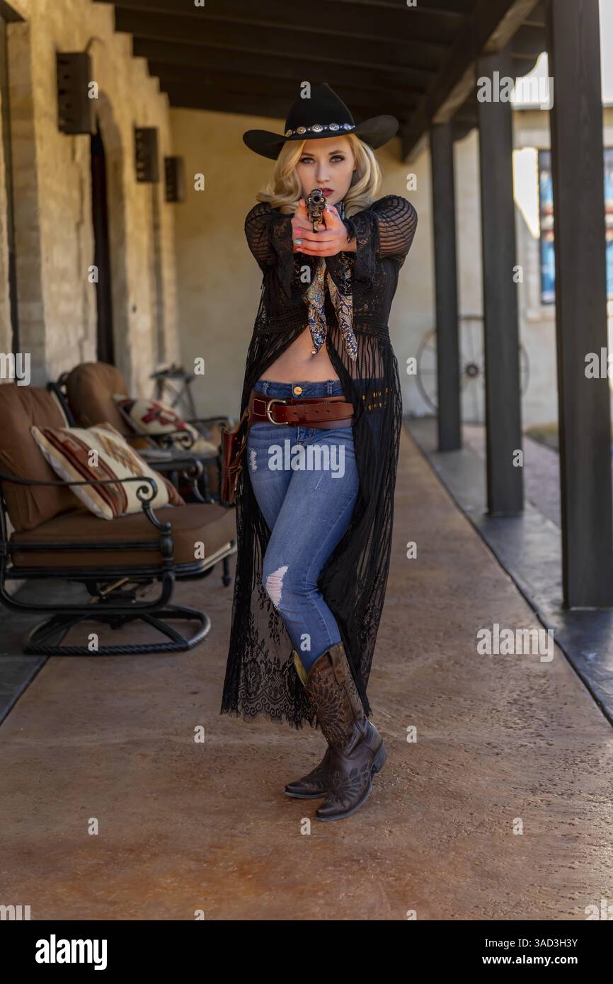 A confident, beautiful blonde woman in classic cowboy attire stands ...