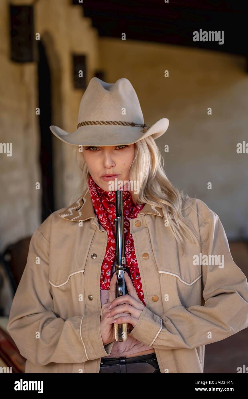 A confident, beautiful blonde woman in classic cowboy attire stands ...