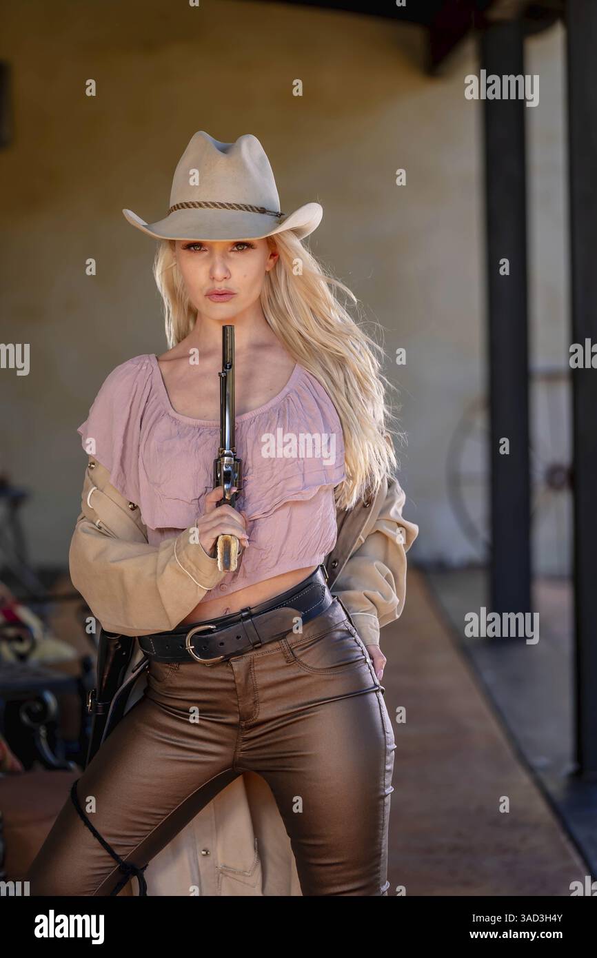 A confident, beautiful blonde woman in classic cowboy attire stands ...