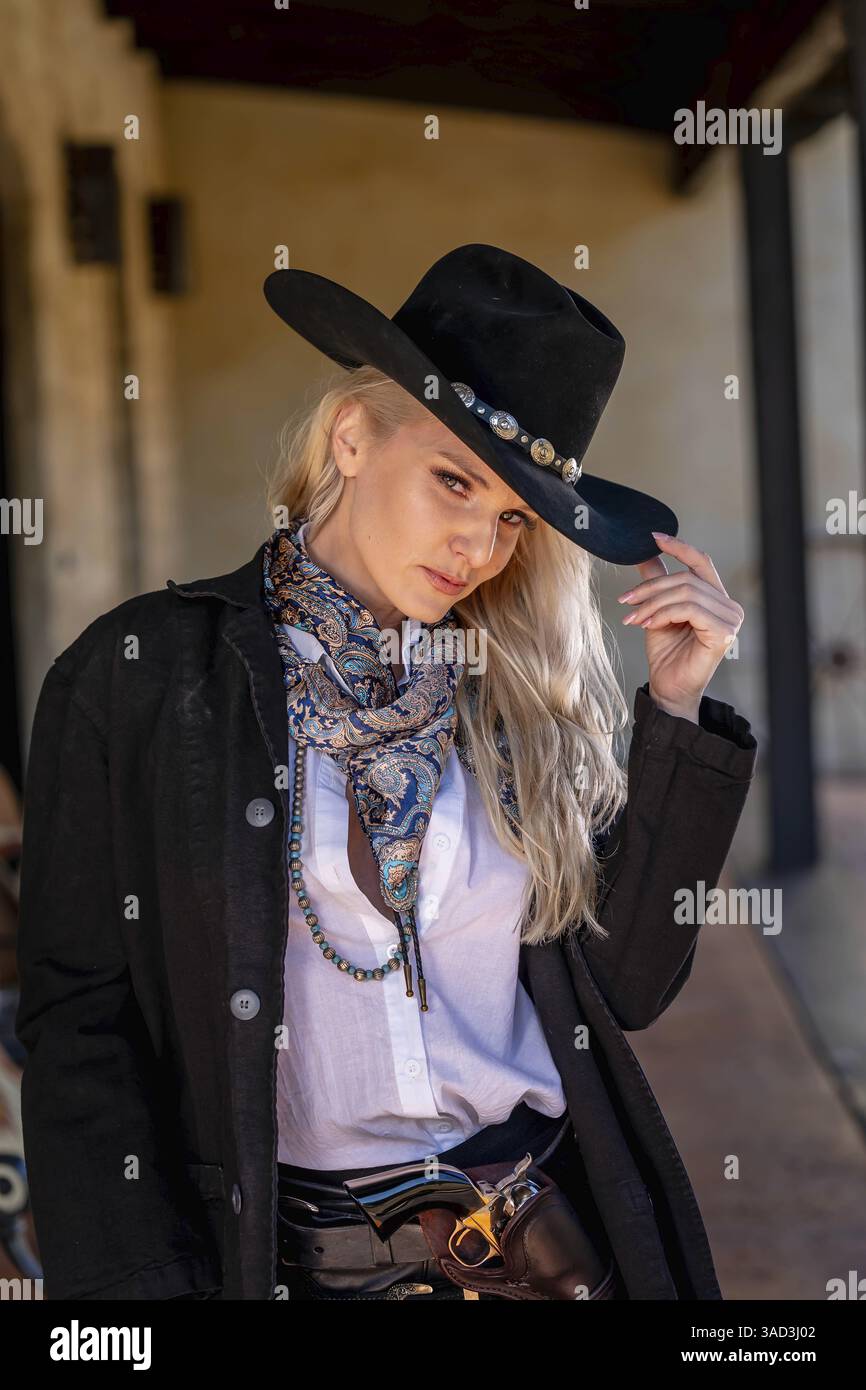 A confident, beautiful blonde woman in classic cowboy attire stands ...