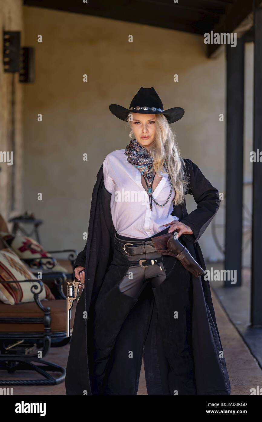 A confident, beautiful blonde woman in classic cowboy attire stands ...